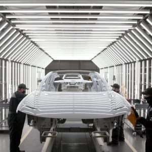 The photo depicts a car manufacturing facility where a car, in its ...